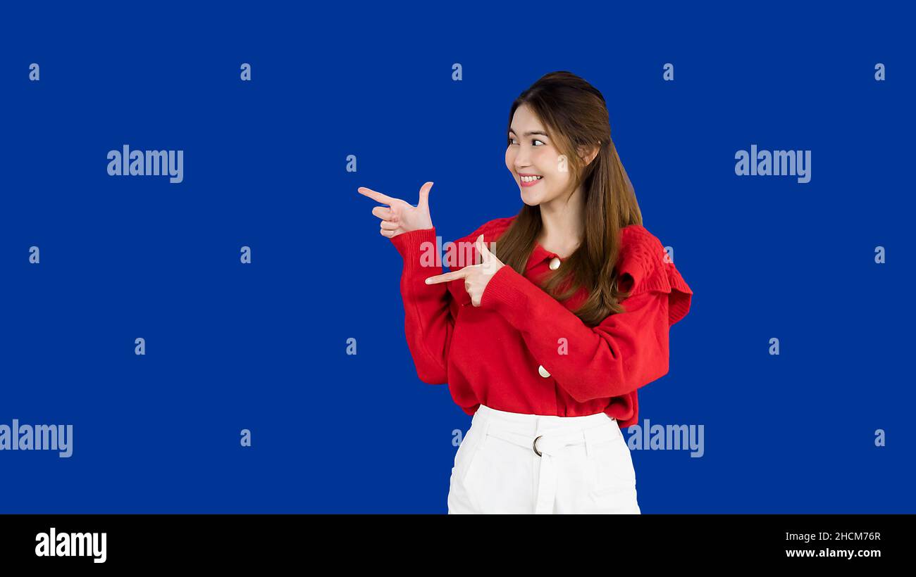 Portrait of an Asian female pointing left with her fingers with a smile ...