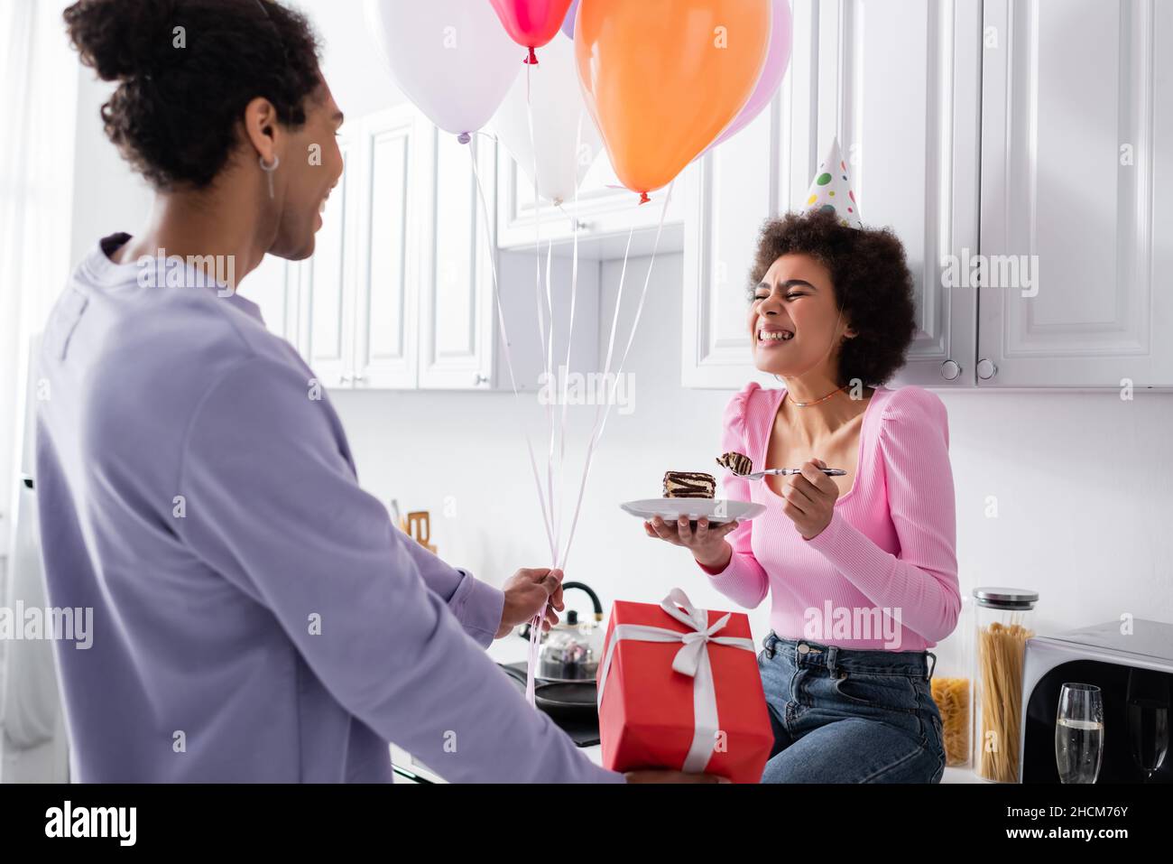 Happy african american woman holding cake near boyfriend with balloons ...