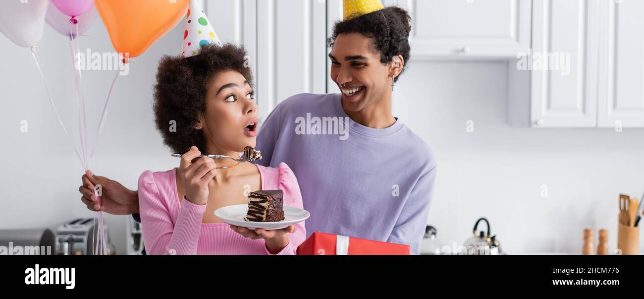 Excited african american woman holding birthday cake near boyfriend ...
