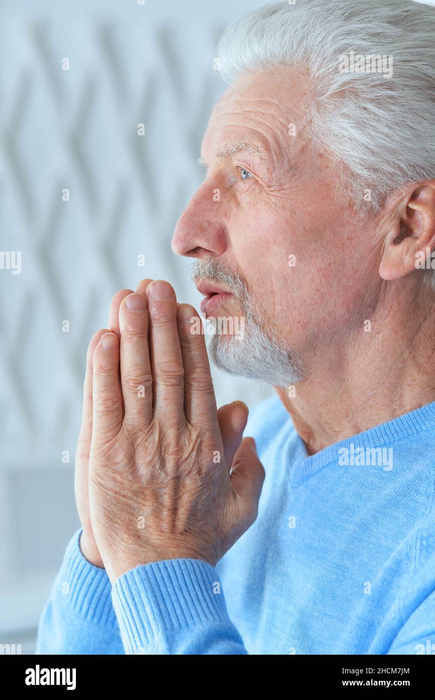 Portrait of sad senior man at home praying Stock Photo - Alamy