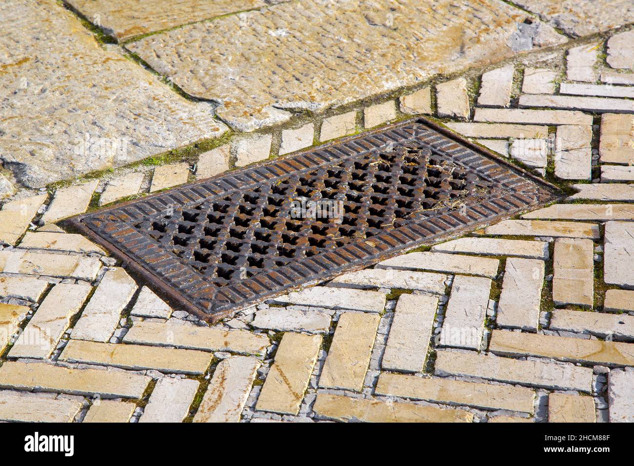 iron rusty rectangular manhole with shaped holes in form of crosses in ...