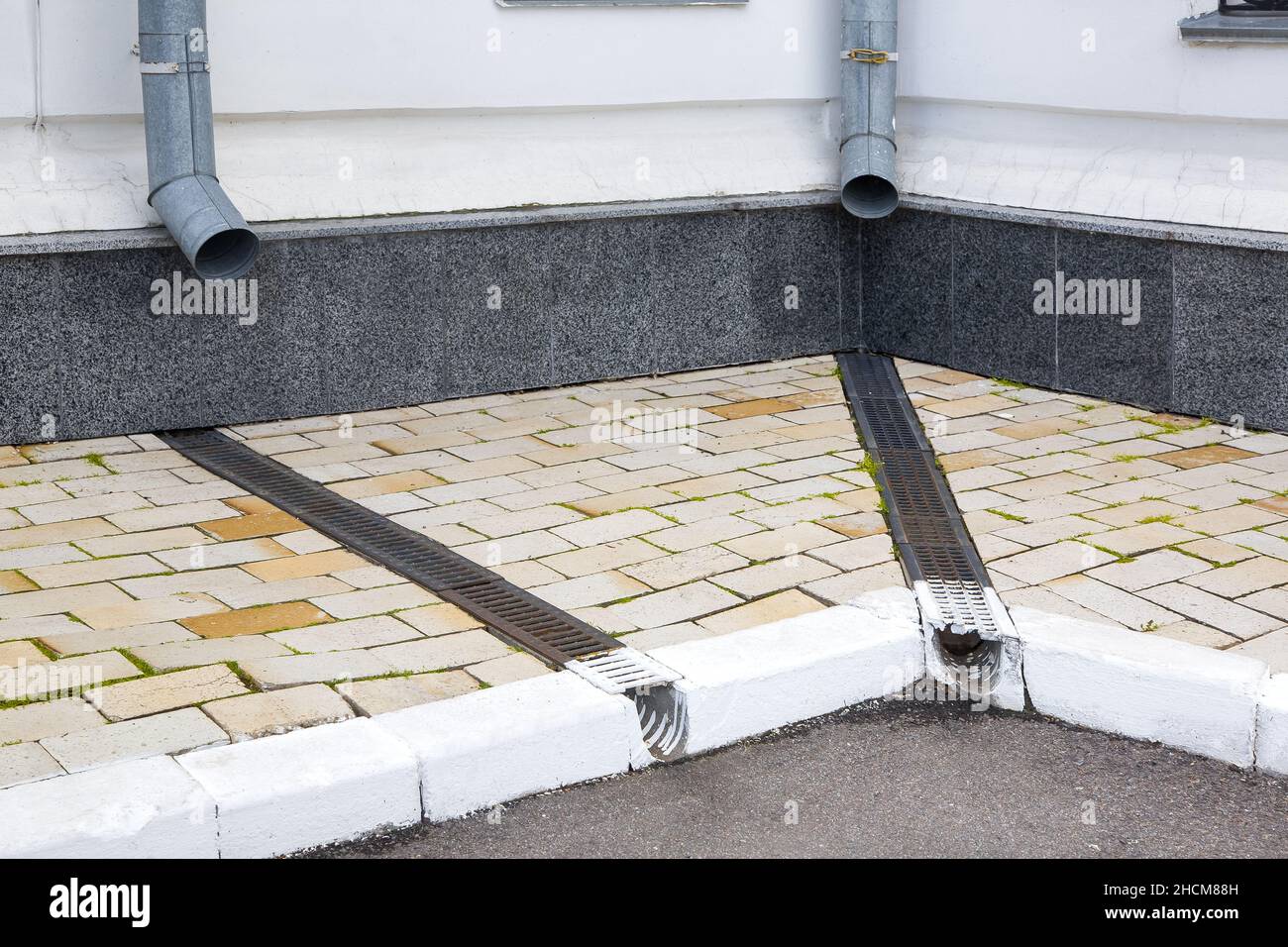 facade of a building wall with a downspout pipe and a concrete dish ...