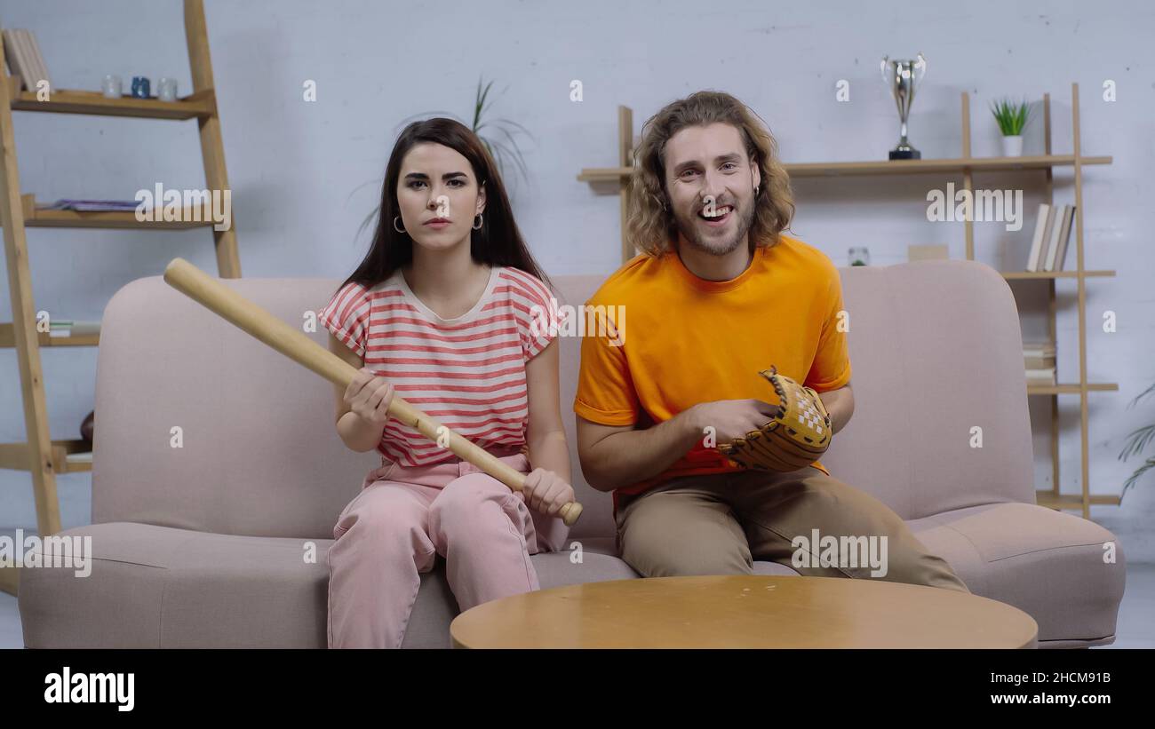 concentrated woman holding baseball bat while watching match near ...