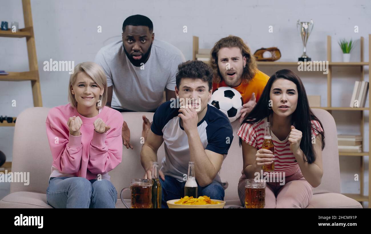 worried women watching football match with multiethnic friends and ...