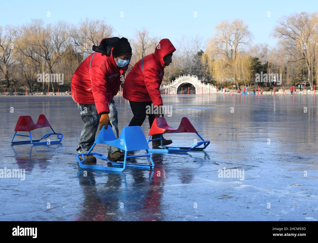 Beijing, China. 30th Dec, 2021. Staff members prepare sleds on a frozen ...