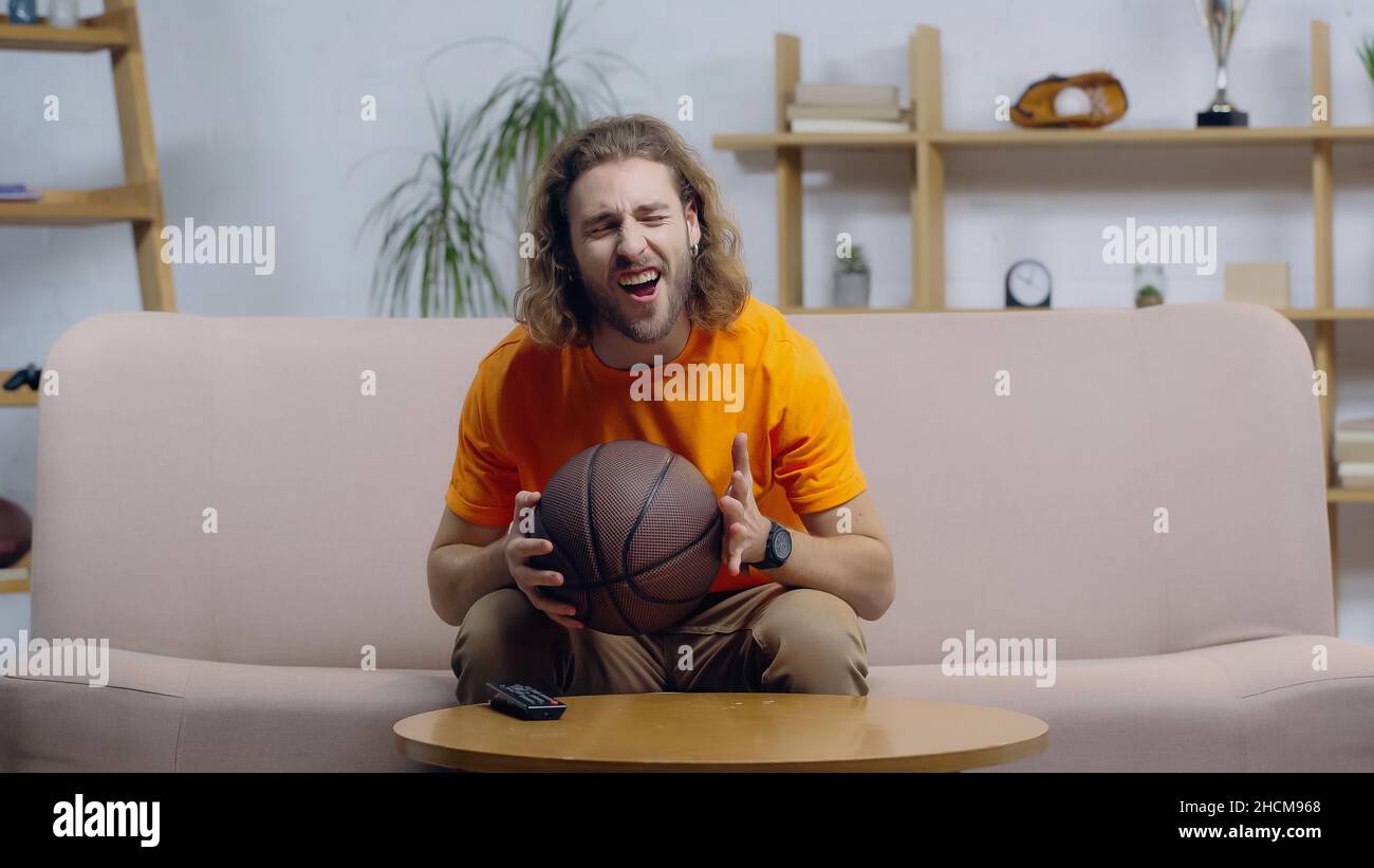 excited sport fan shouting while watching basketball match on couch at ...
