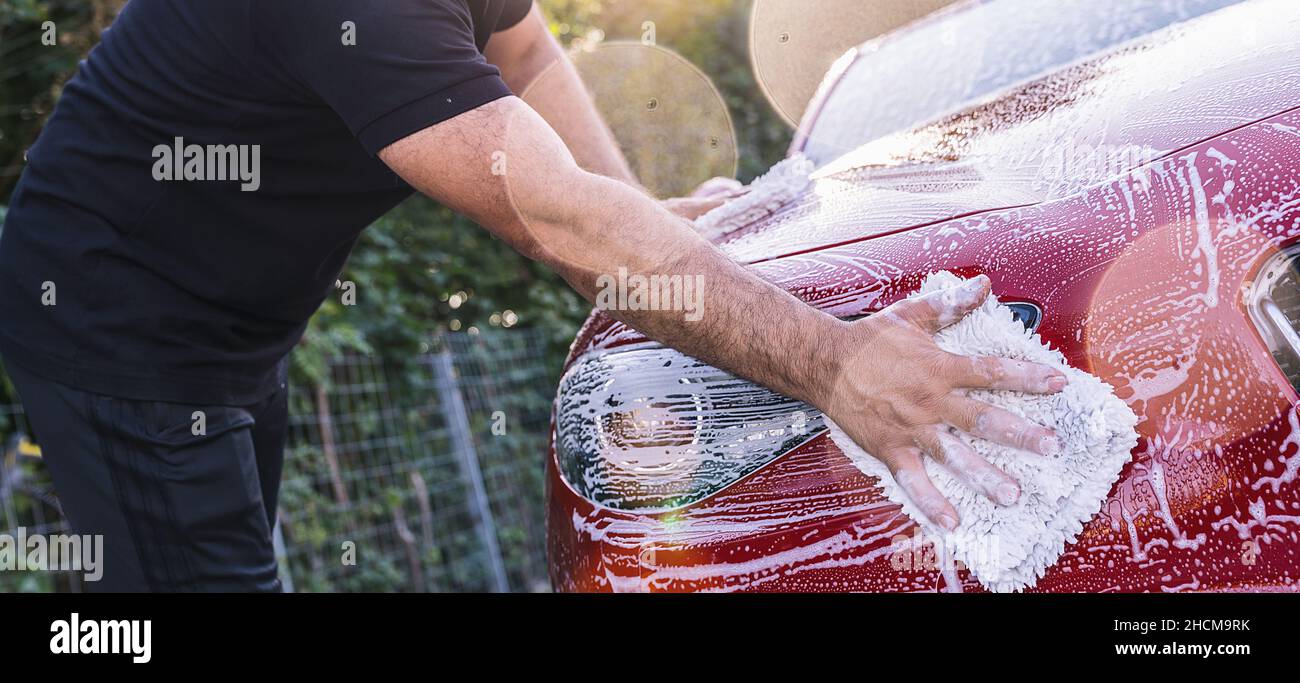 Man worker washing a red car with sponge on a car wash Stock Photo - Alamy
