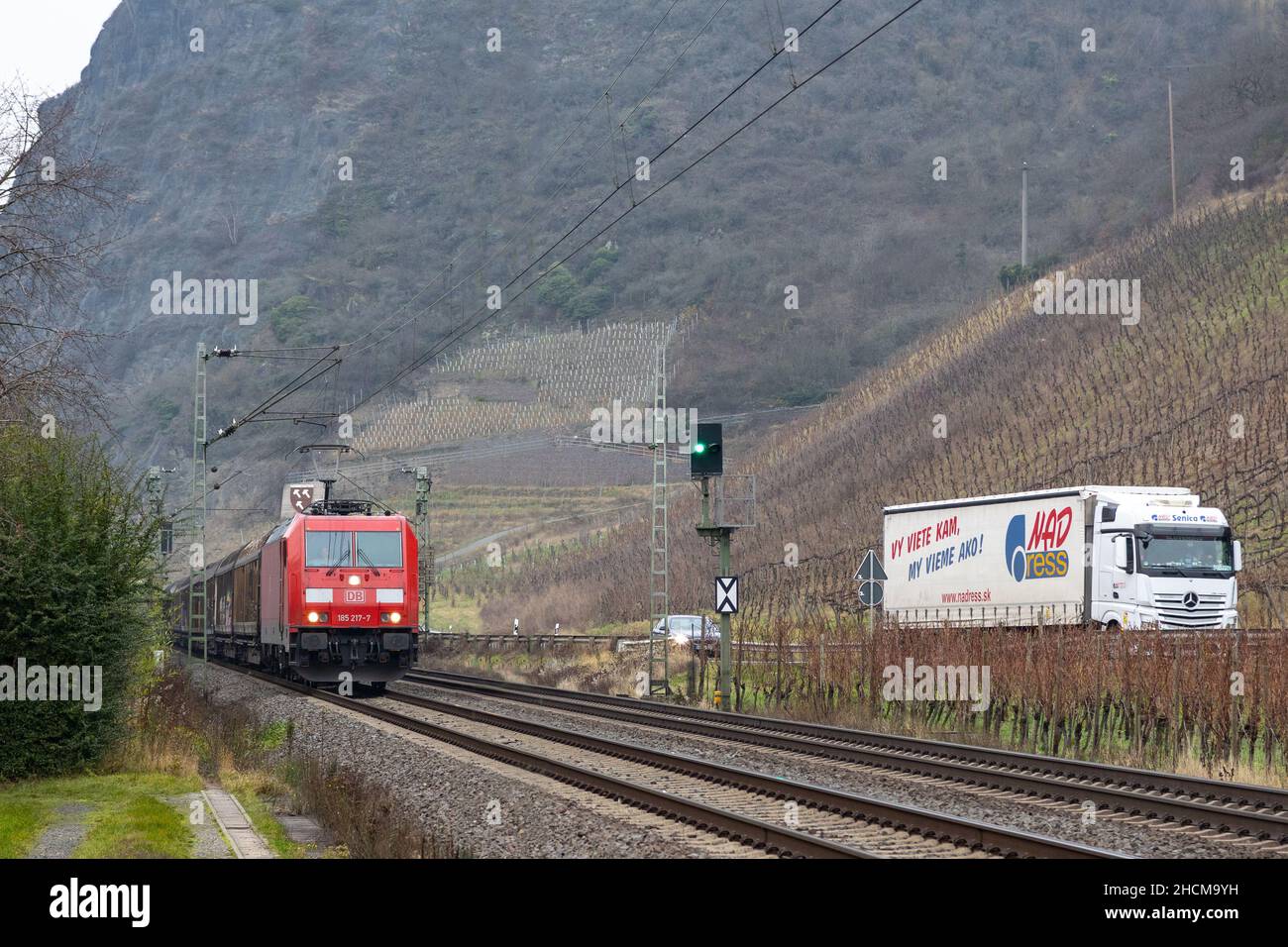 A freight train with a red electric locomotive side by side with a ...