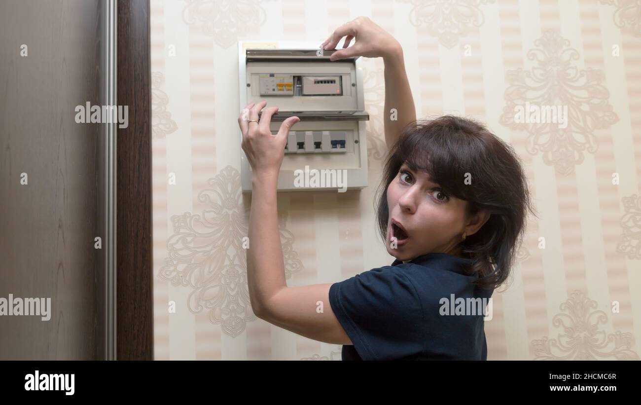 An adult woman looks electric meter readings with horror and surprise ...