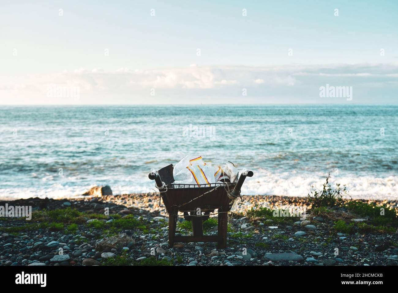 Wheelbarrow full of plastic waste stand on beach with sea panorama ...