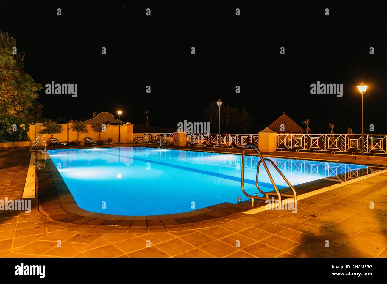 Large empty outdoor hotel swimming pool illuminated at night with black ...