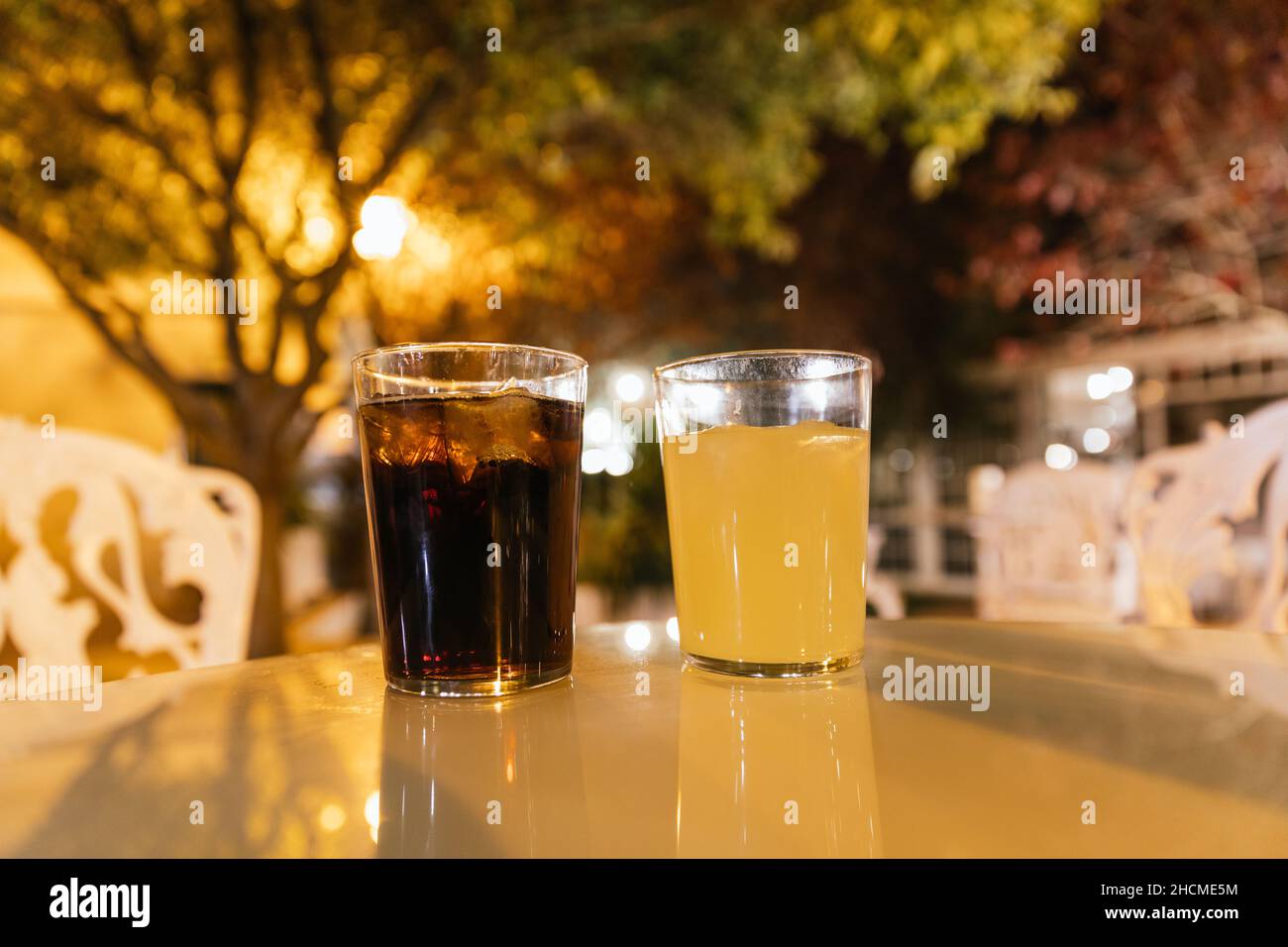 Terrace table in the evening with two drinking glasses, coke and lemon ...
