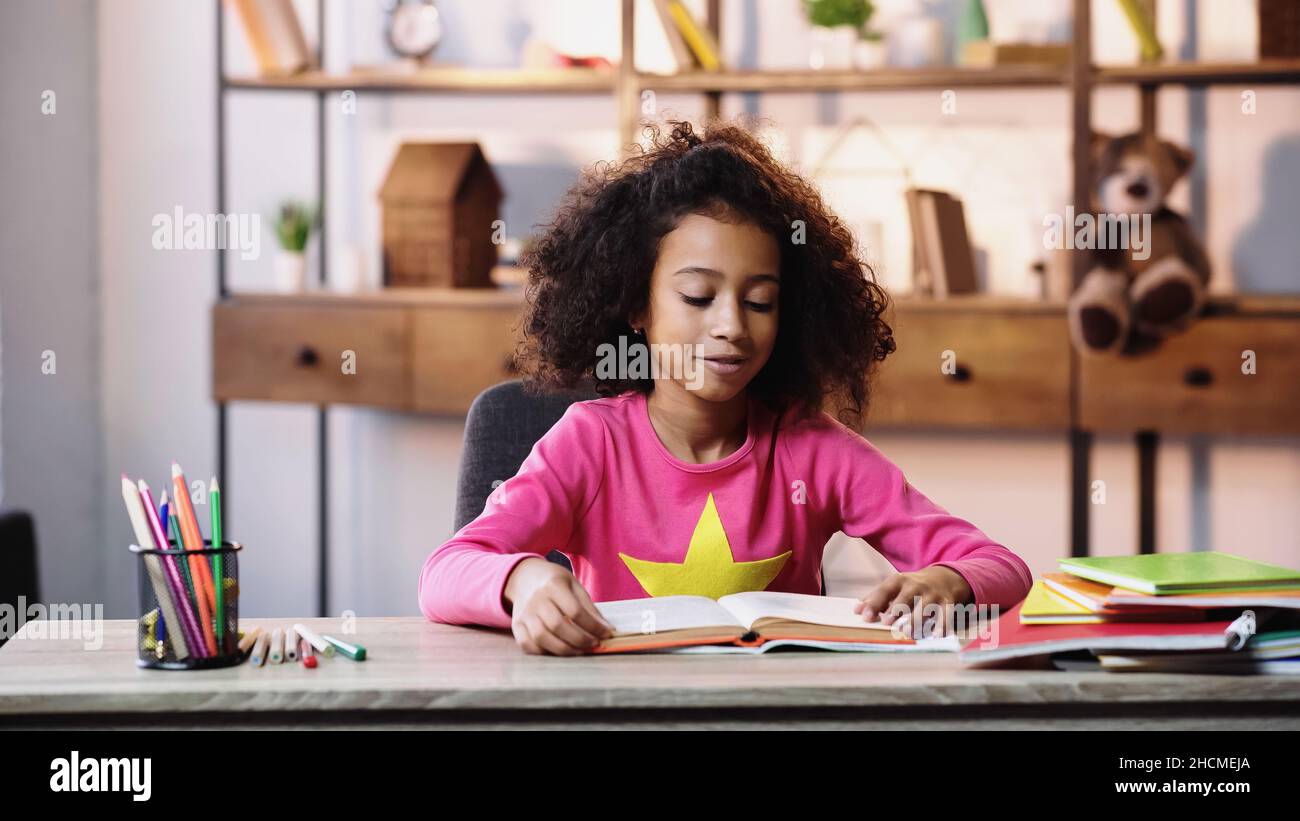 smiling african american child reading book at home Stock Photo - Alamy