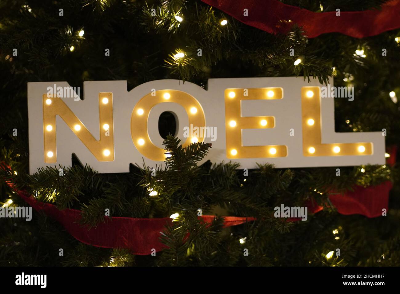 Photo of a lit noel sign ornament on a lighted Christmas tree and red ...