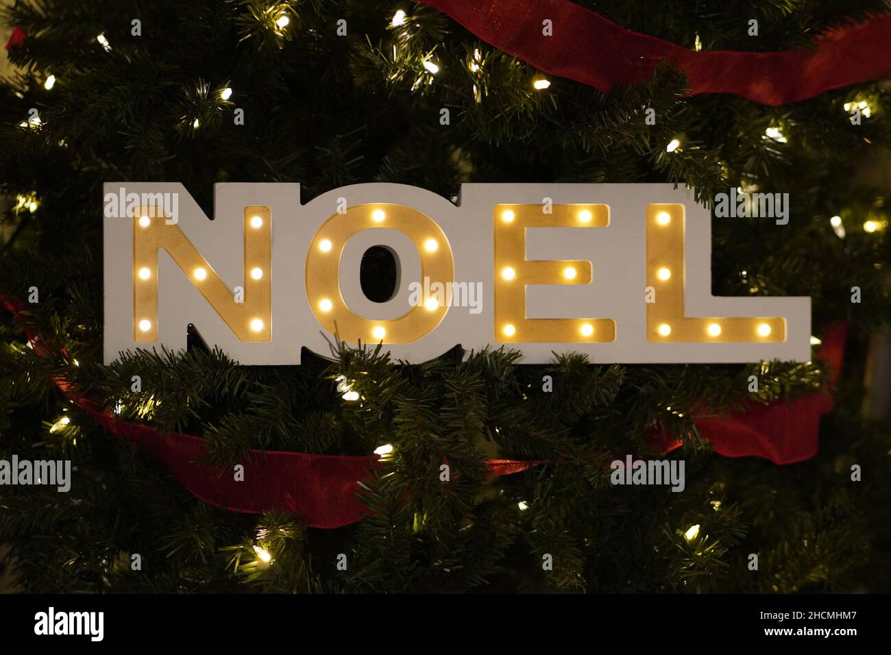 Photo of a lit noel sign ornament on a lighted Christmas tree and red ...