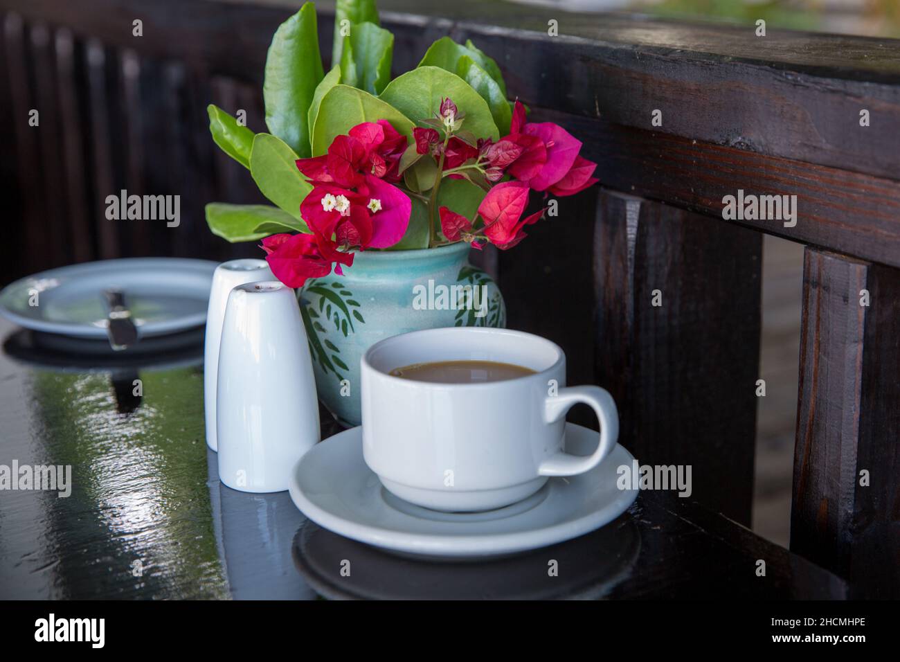 Cup of coffee and a flower vase on the cafe table Stock Photo - Alamy