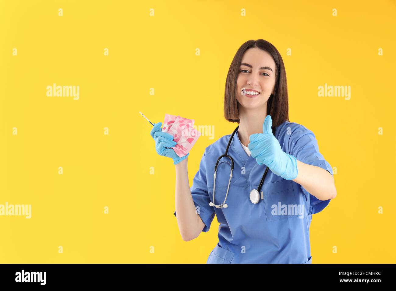 Female nurse with pads and pregnancy test on yellow background Stock ...