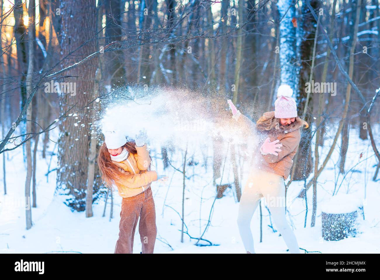 Two teenage girls having fun playing with snow, throwing snowballs ...