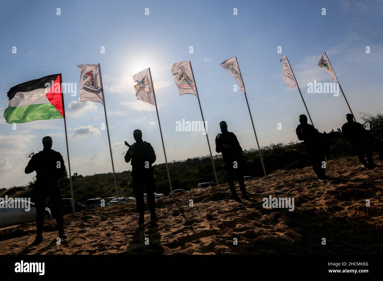 Palestinian fighters stand while the flags of the Palestinian military ...