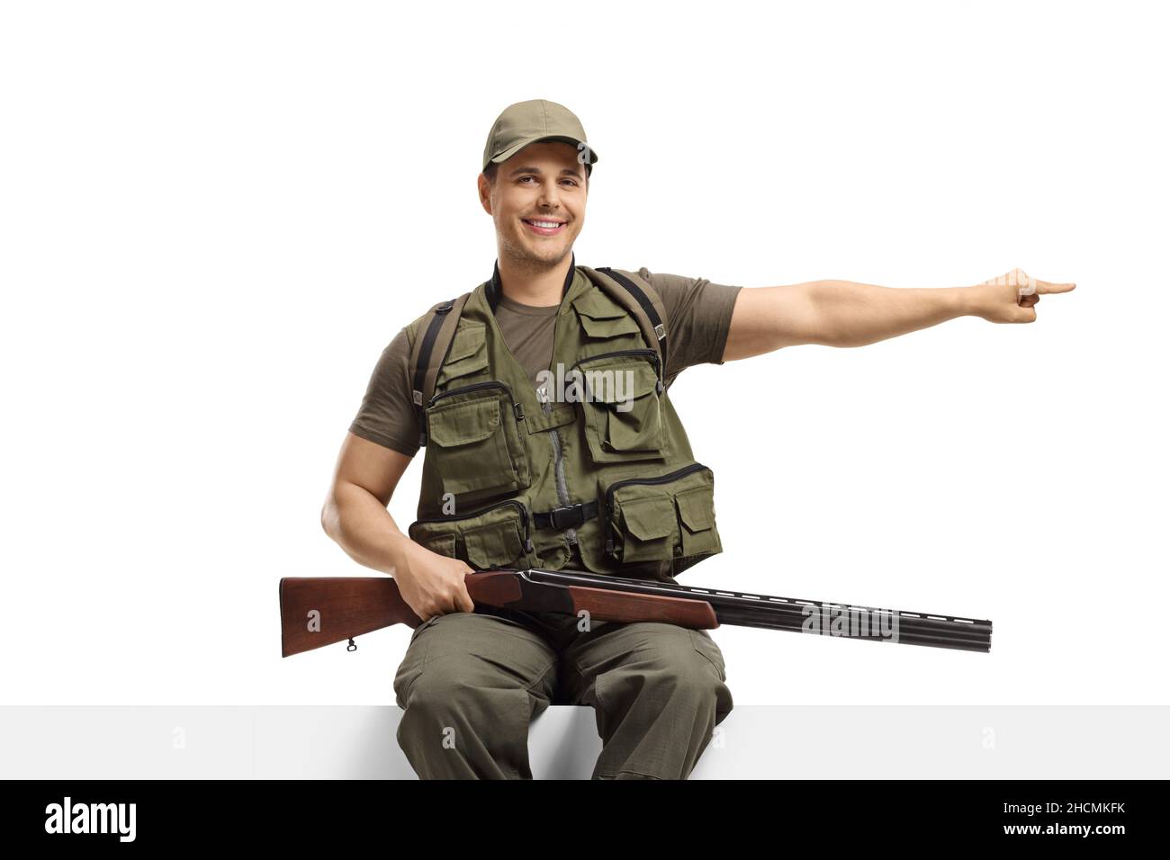 Hunter with a rifle sitting on a panel and pointing to the side ...