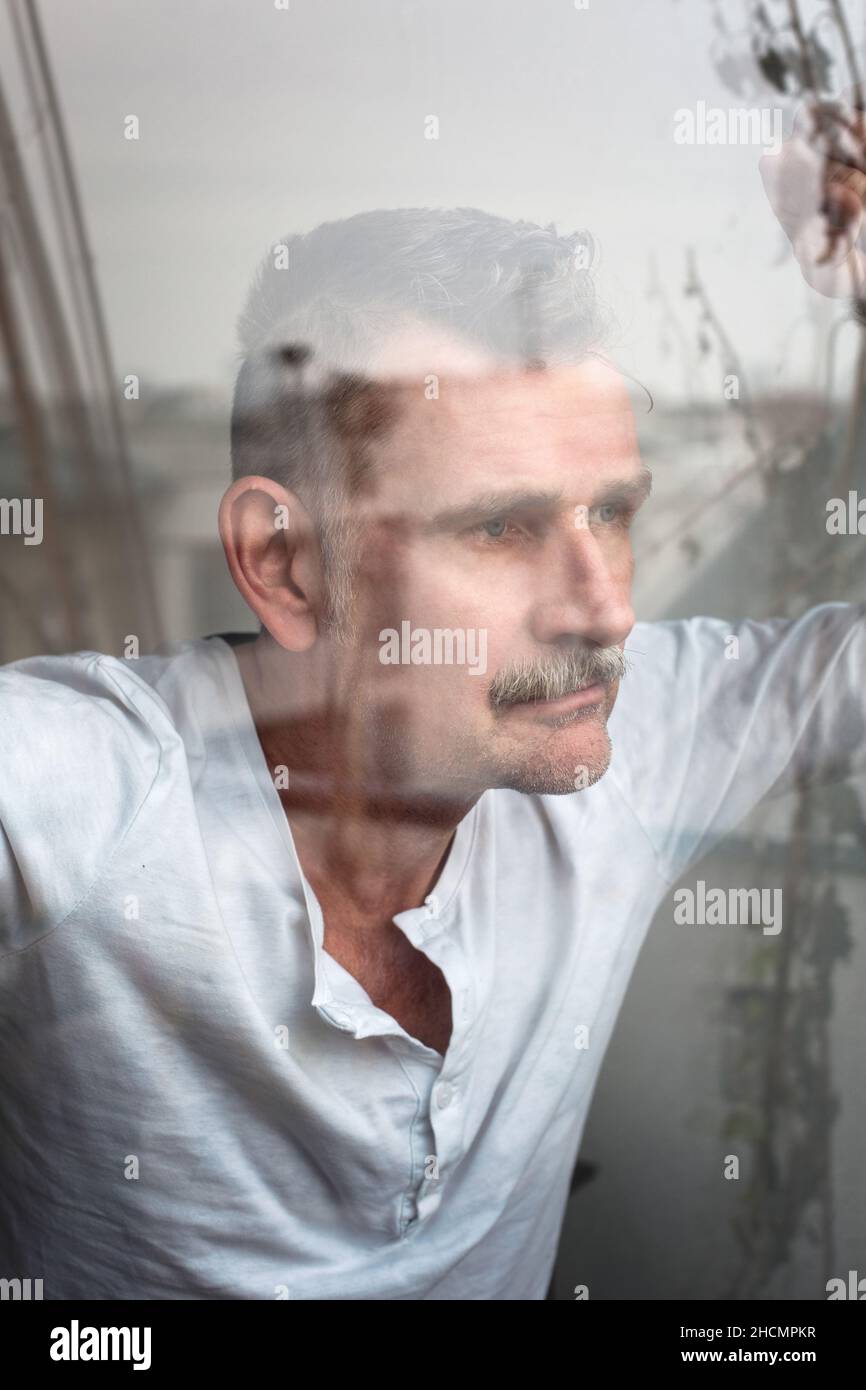 portrait of handsome man in his 50s looking out of window Stock Photo ...