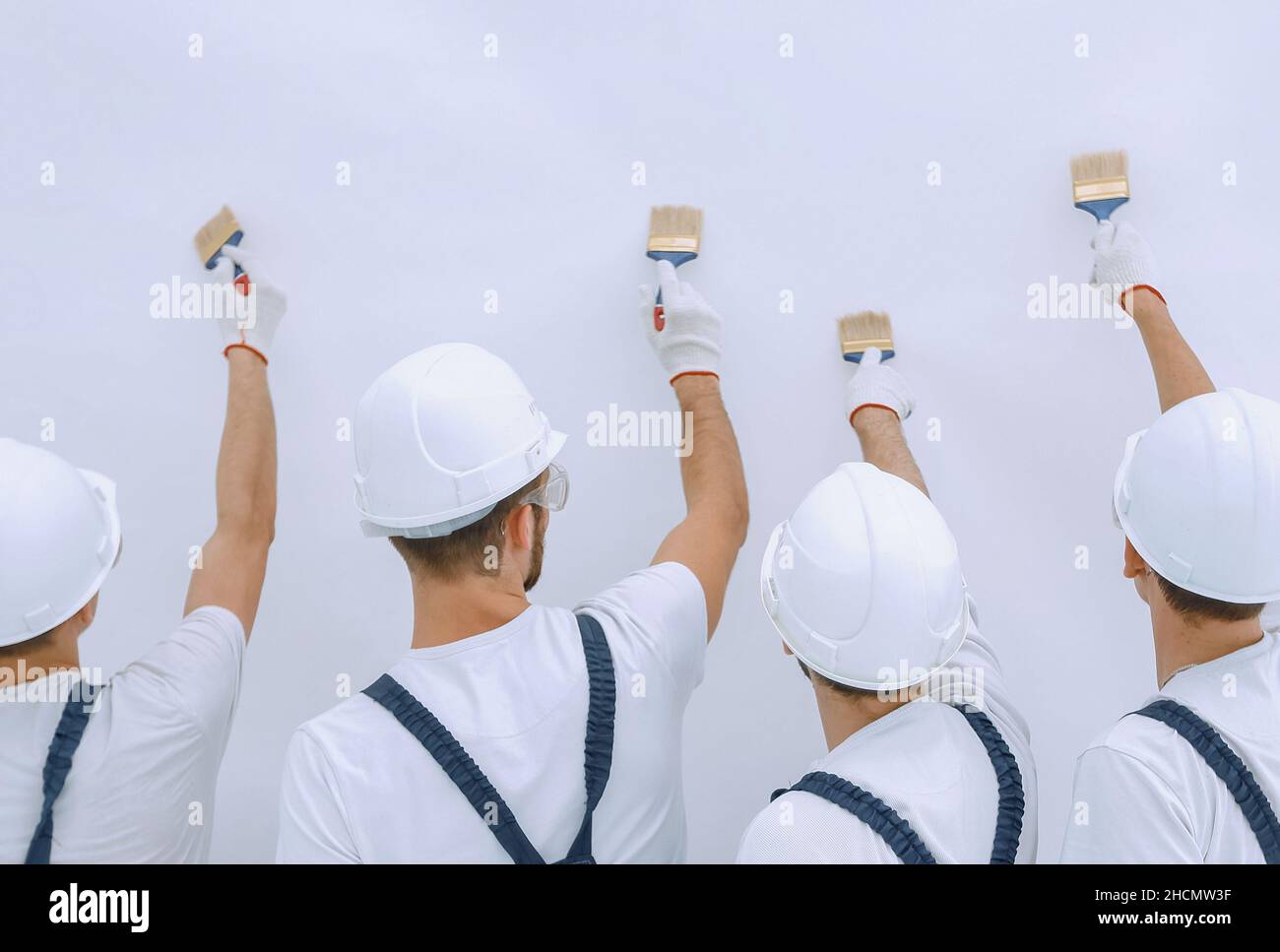 rear view.construction workers paint the wall Stock Photo - Alamy