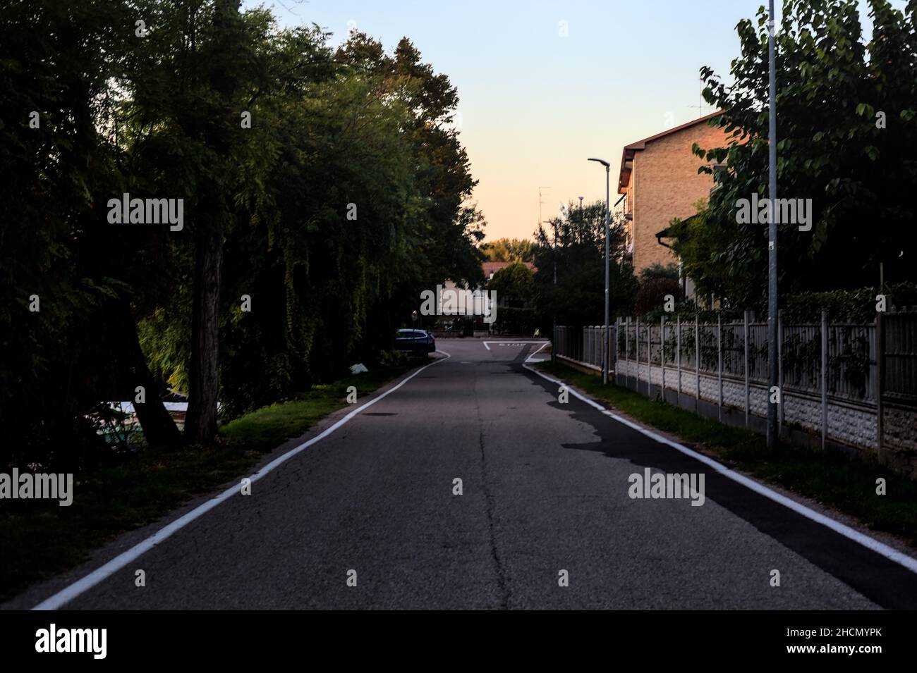 Street by the shore of a lake at sunset in the italian countryside ...