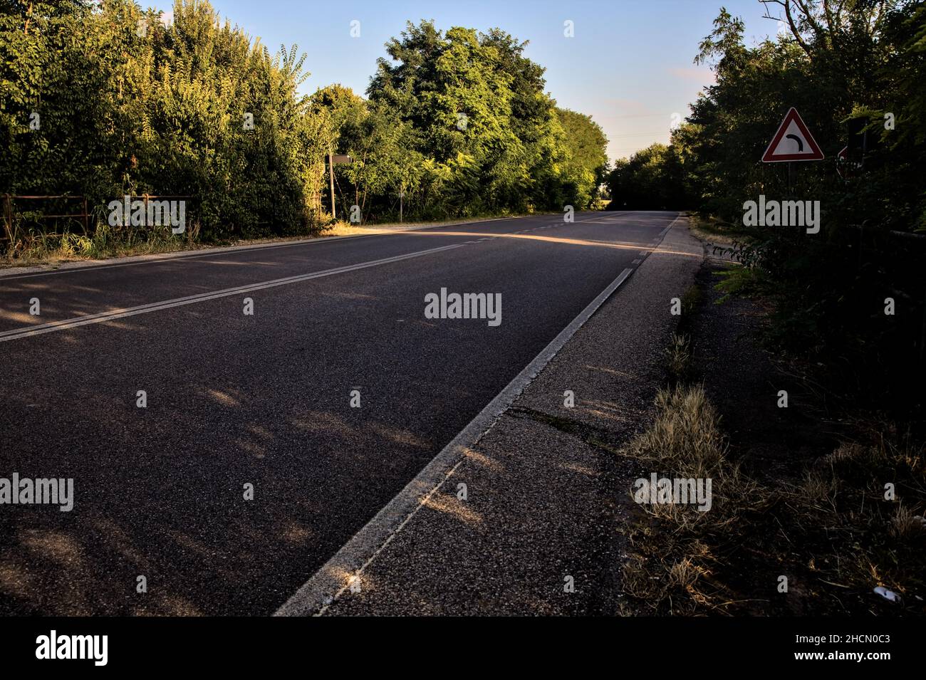 Bend of a road bordered by trees in the countryside at sunset Stock ...