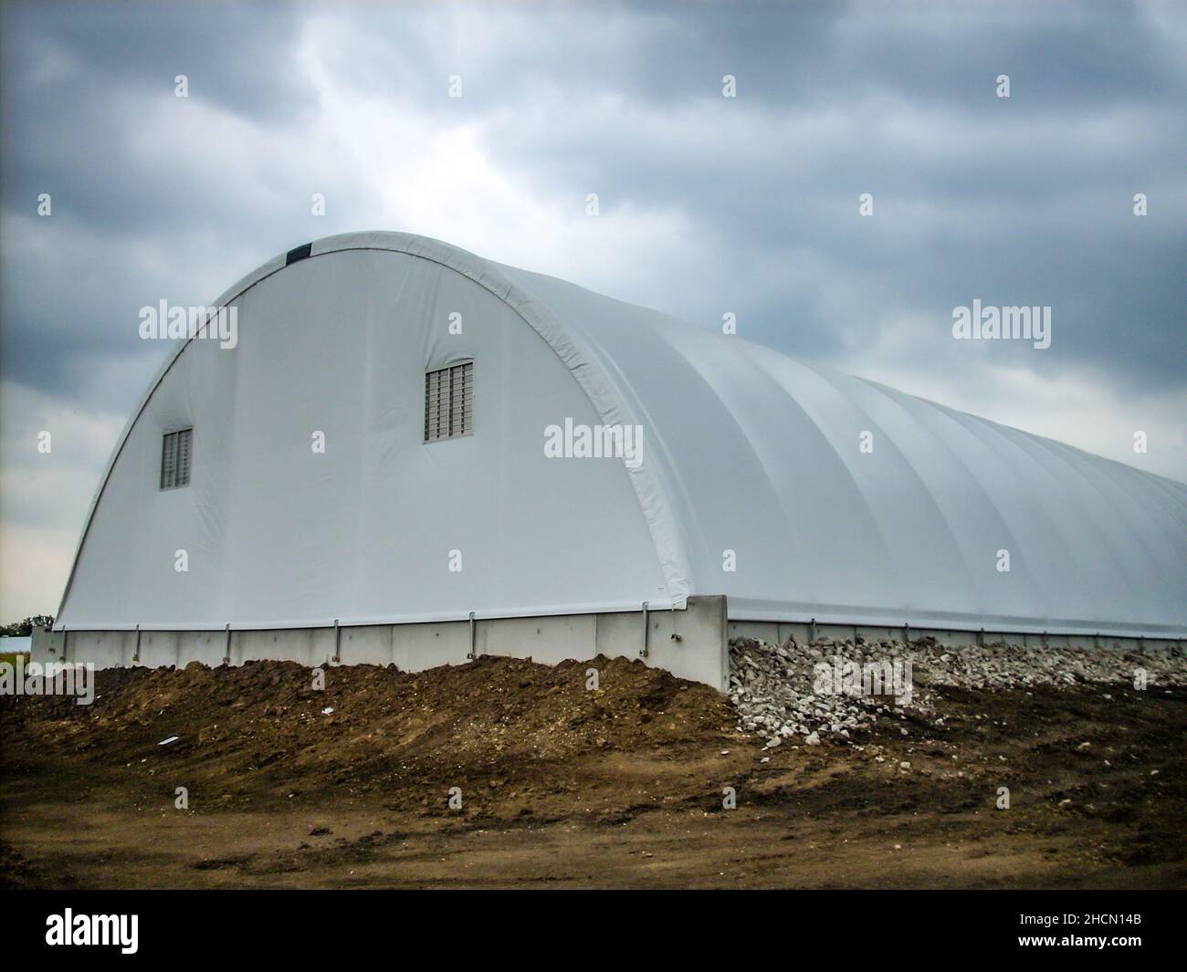 Prefabricated hoop barn with a tarp covering against a cloudy sky Stock ...