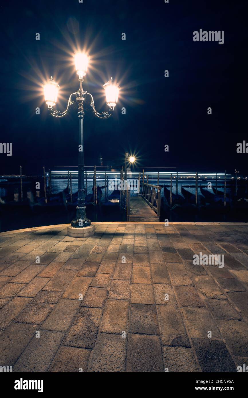 Italy, Venice Embankment at night. Historical lamp post with goldolas ...