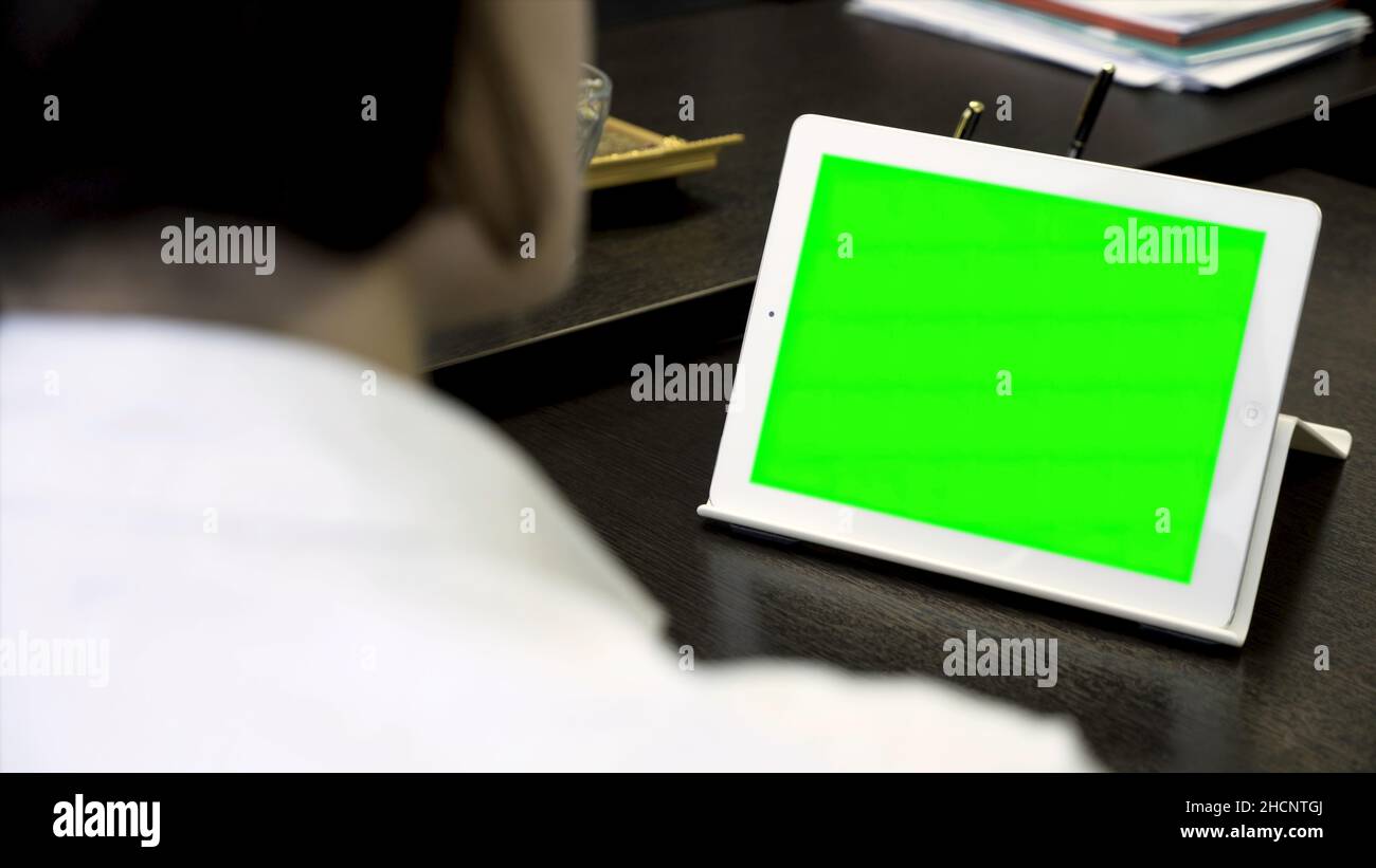 Close up for a woman looking at a white tablet with a green screen ...