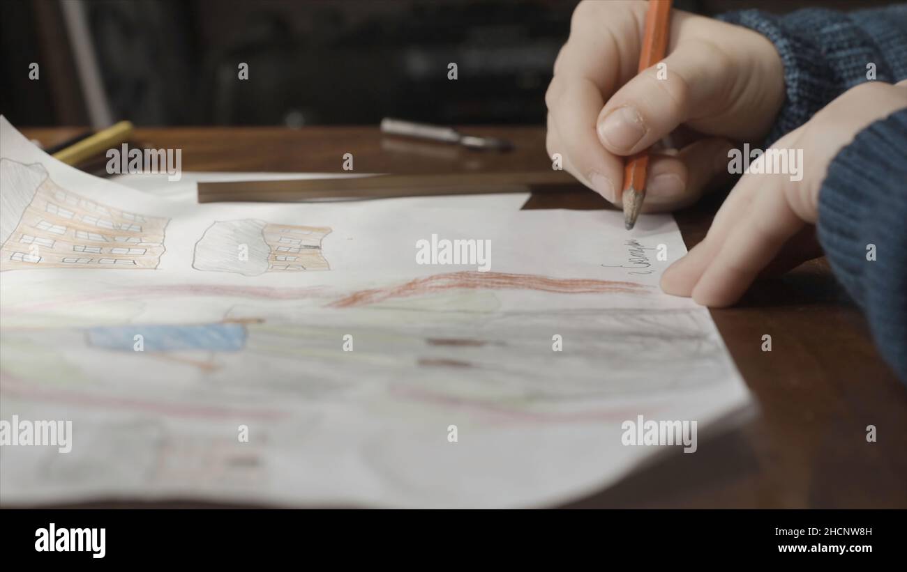 Close up of a boy doing his homework and studying at home. A boy draws ...
