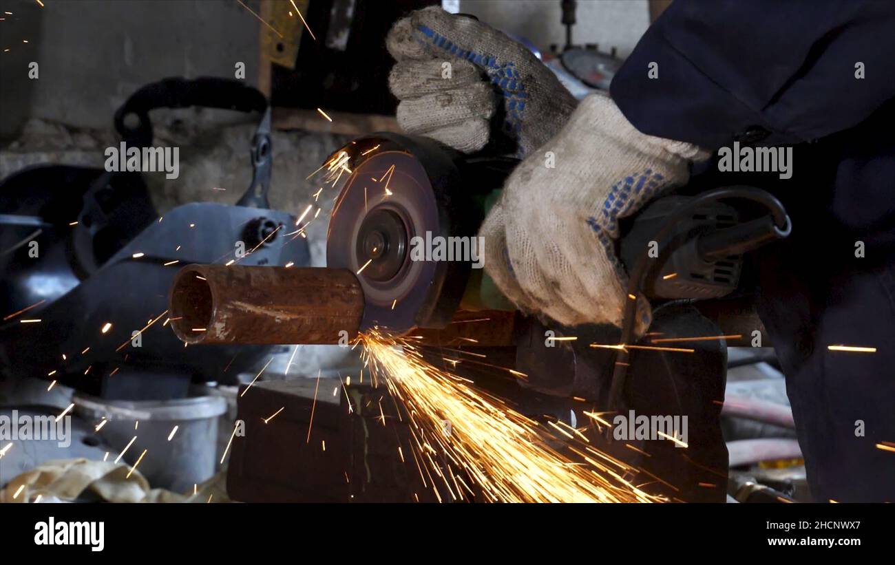 Male hand cuts off pieces of water pipe with angle grinder. Cutting of ...