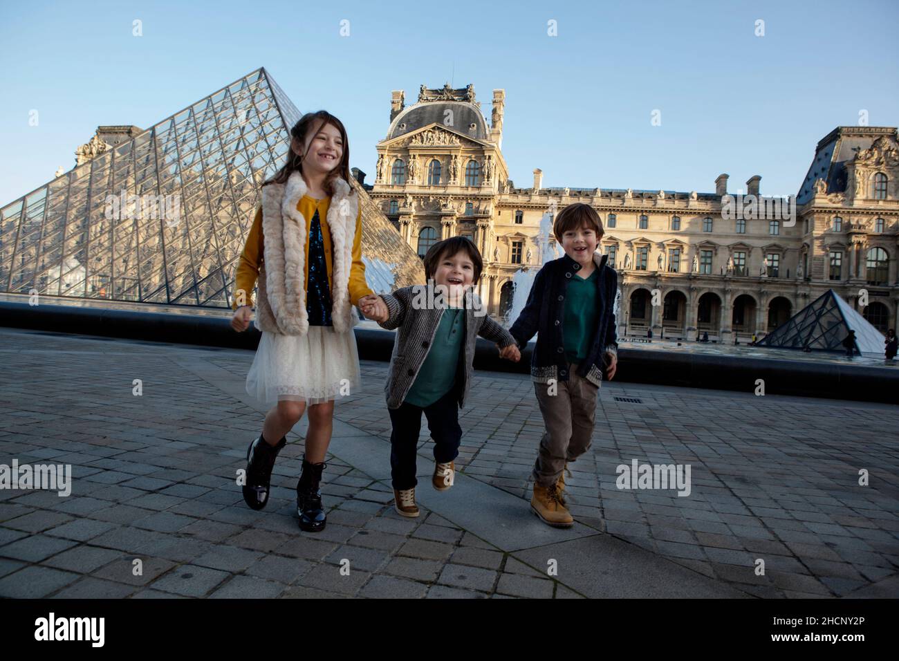 three siblings smile as they visit the Louvre in Paris, France Stock ...