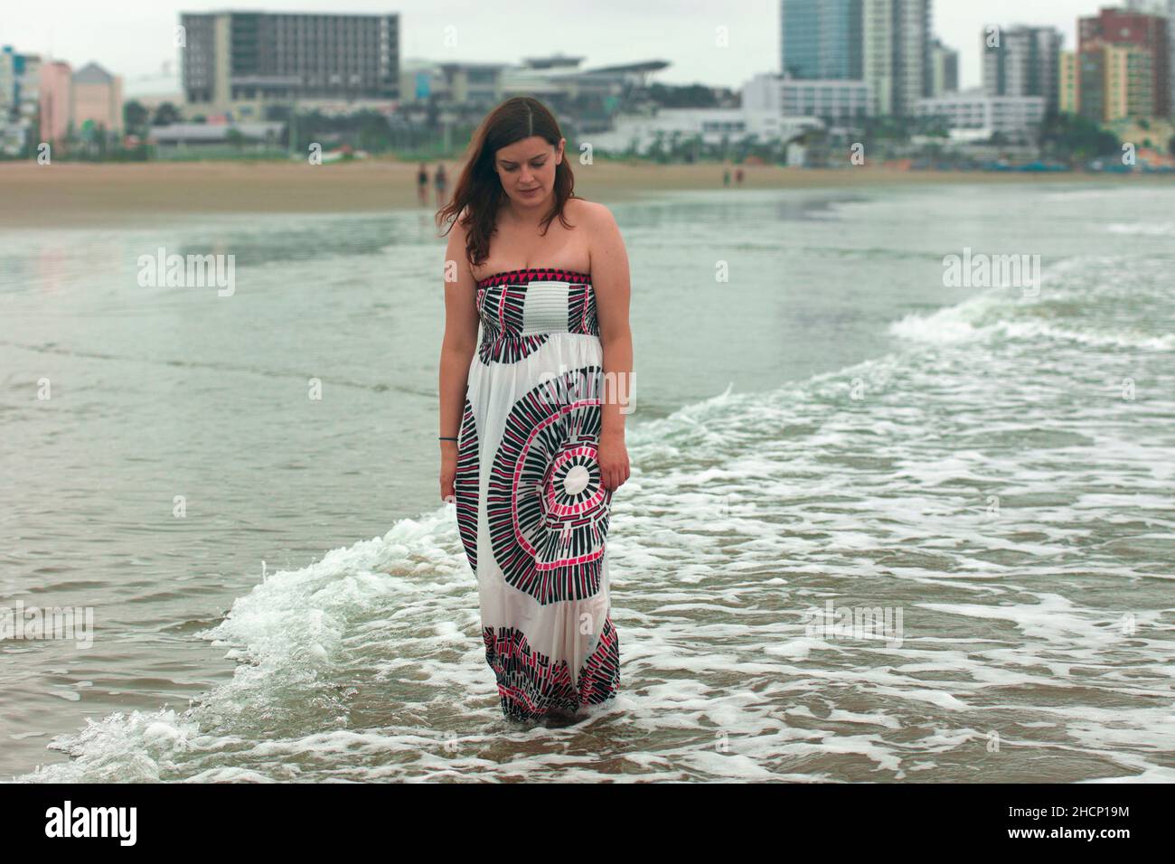 Beautiful Hispanic woman walking calmly into the sea on an empty beach ...