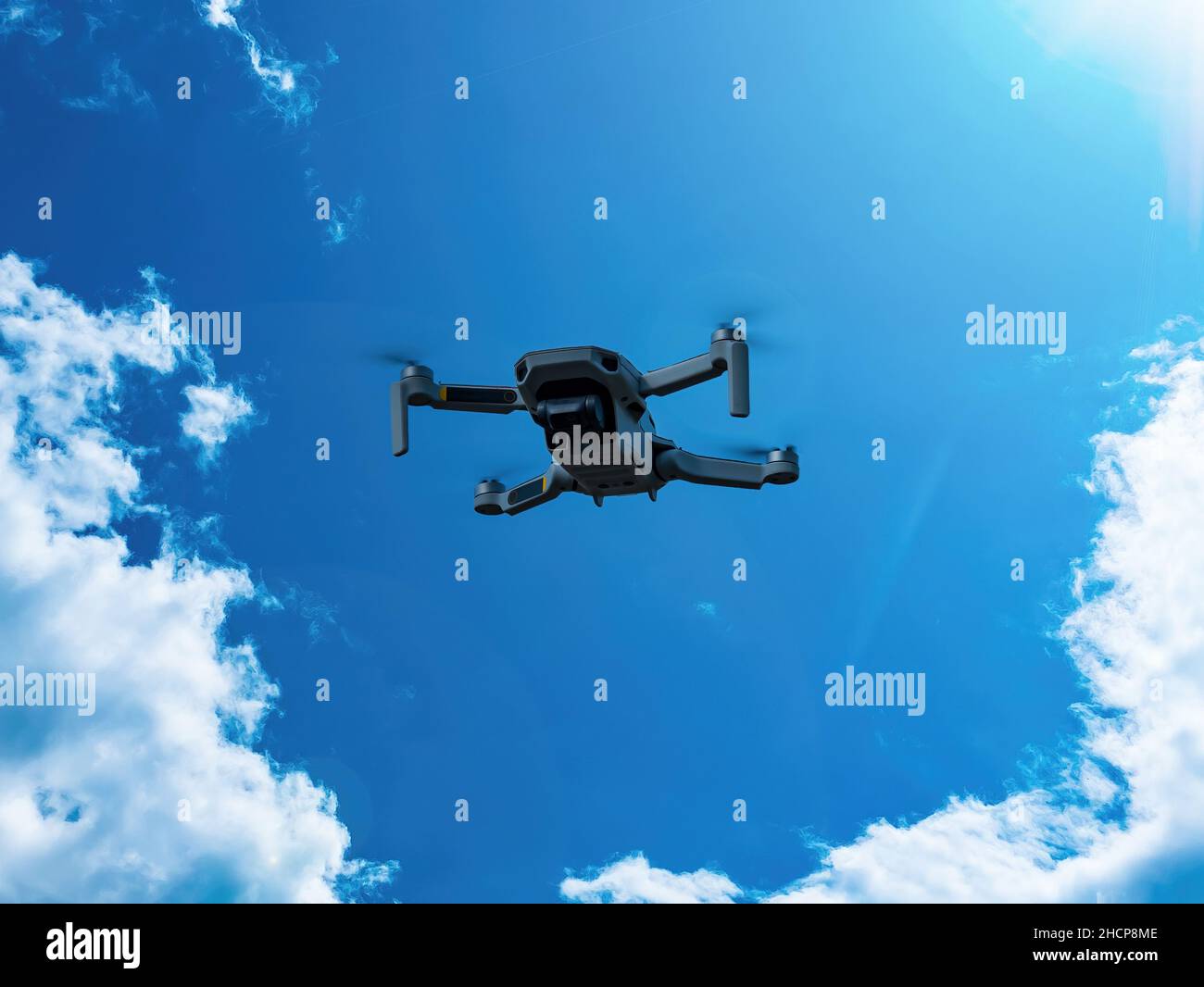 Flying drone against a blue sky with white clouds. Drone in the air ...