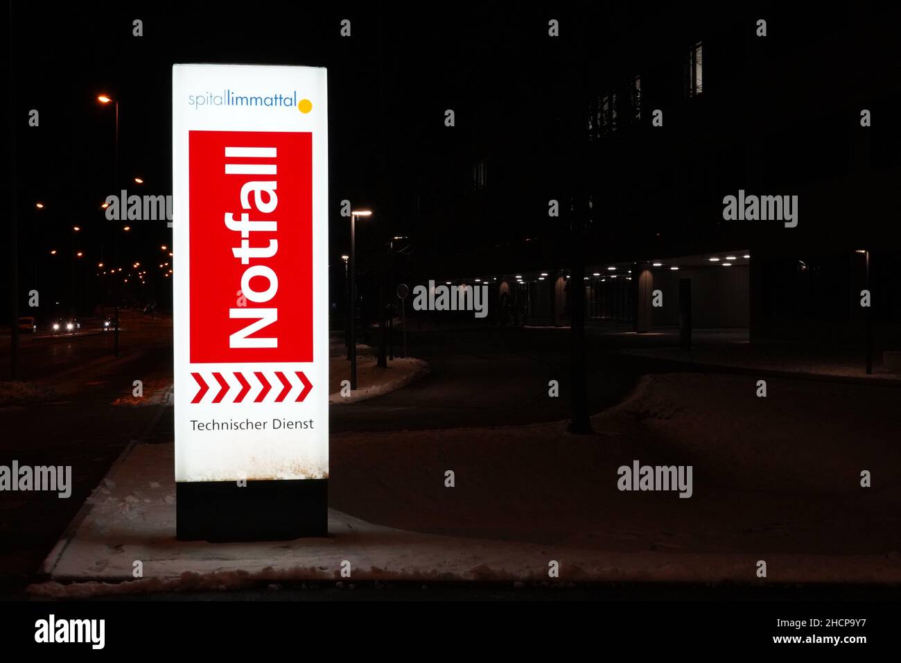 Brightly illuminated signpost at night in red and white saying in ...