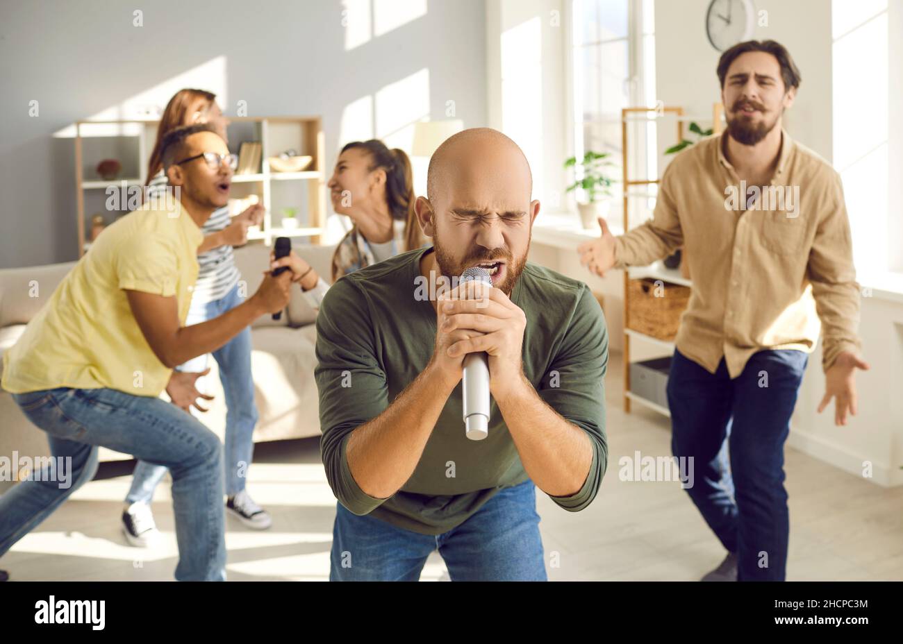 Emotional man holding microphone and enthusiastically singing while ...