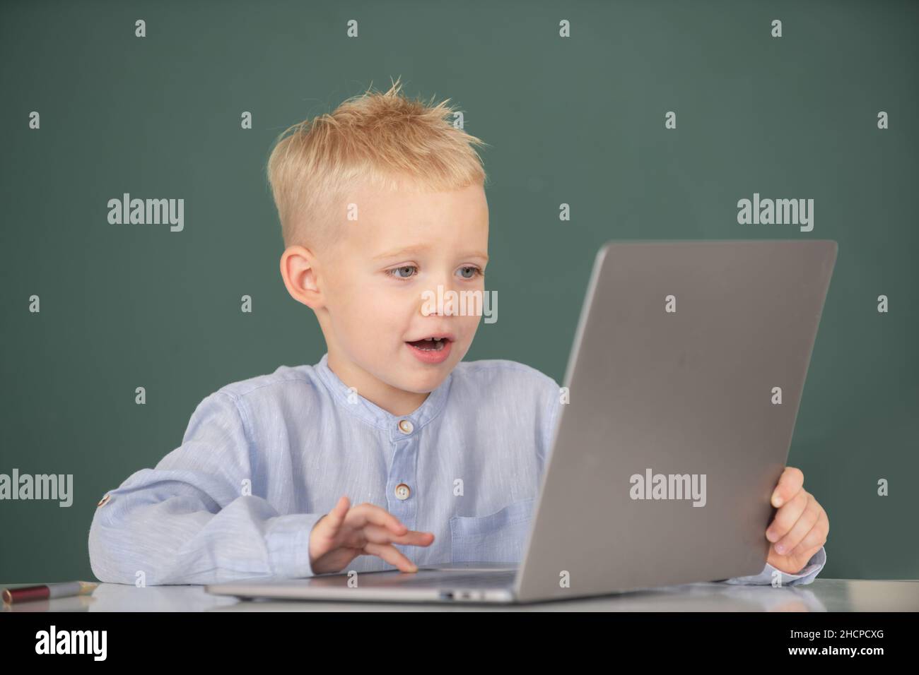 Little student boy using laptop computer in school class. Little funny ...