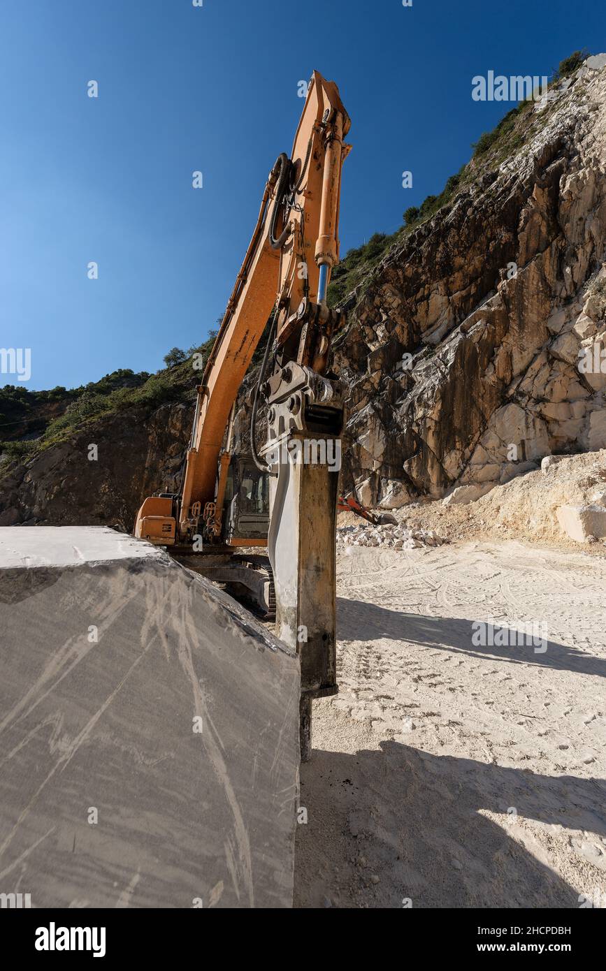 Orange tracker excavator with the jackhammer in a marble quarry ...
