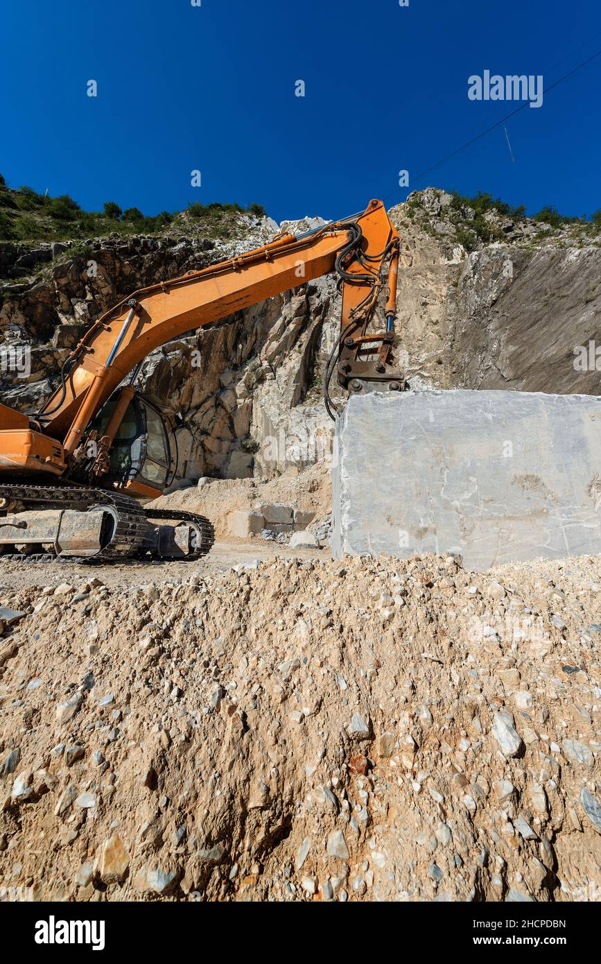 Orange tracker excavator with the jackhammer in a marble quarry ...