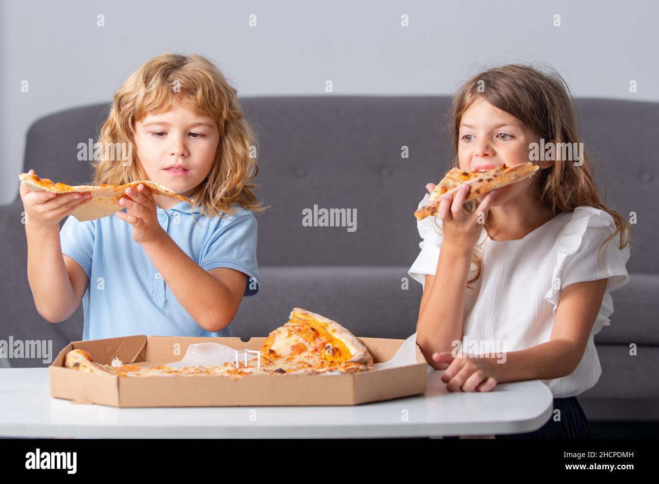 Children eating pizza. Little children friends, boy and girl bite pizza ...