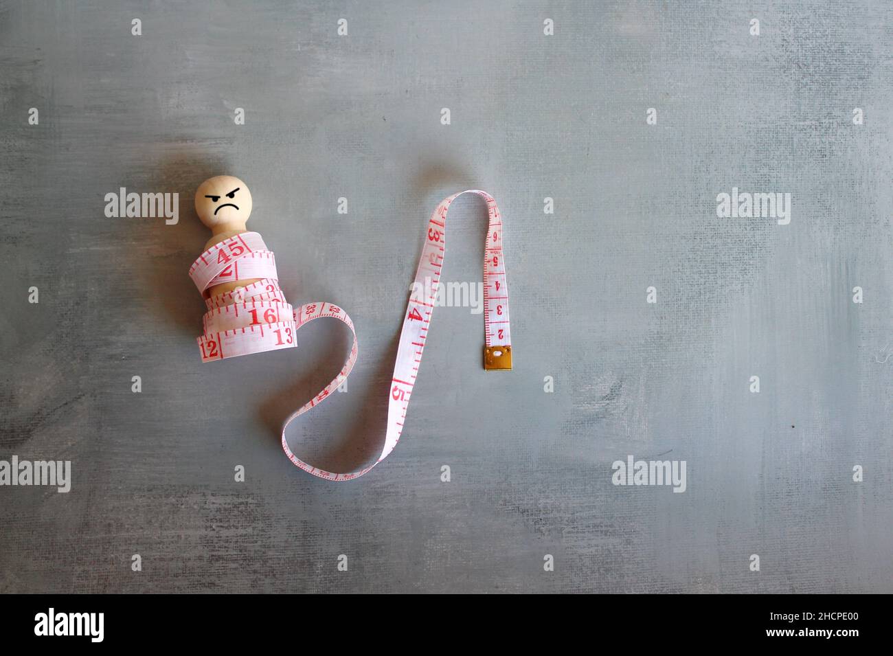 Diet and weight management concept. Wooden doll with angry face and ...