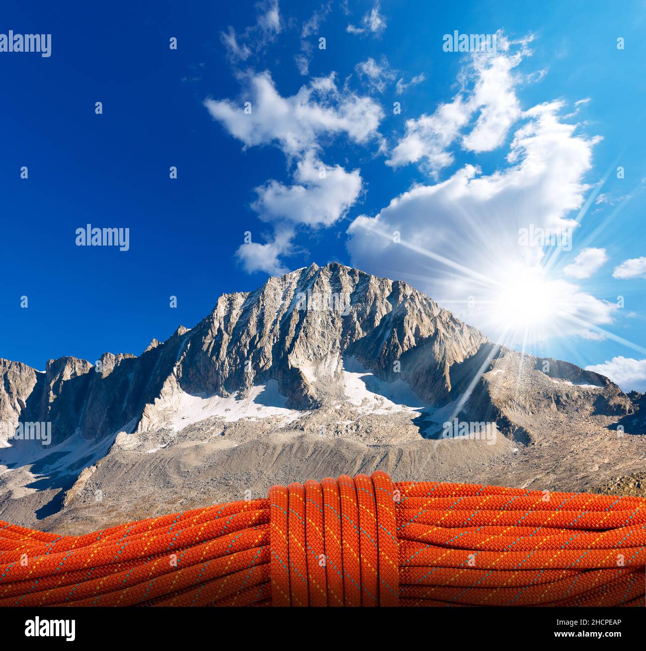 Red climbing rope with a mountain peak on background with blue sky and ...