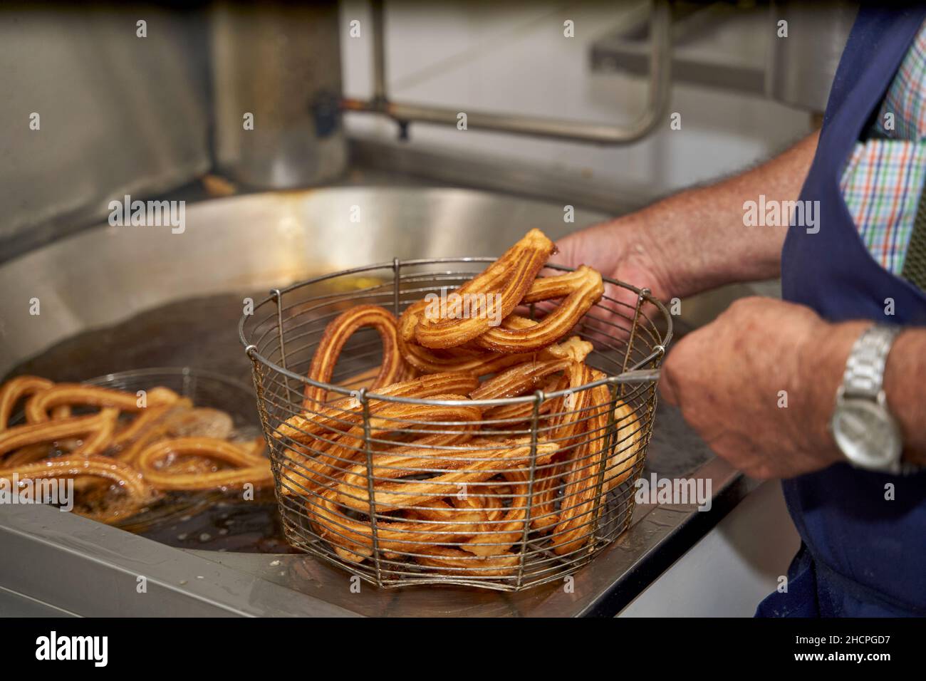 Unrecognizable senior cook removing churros from the boiling oil and ...