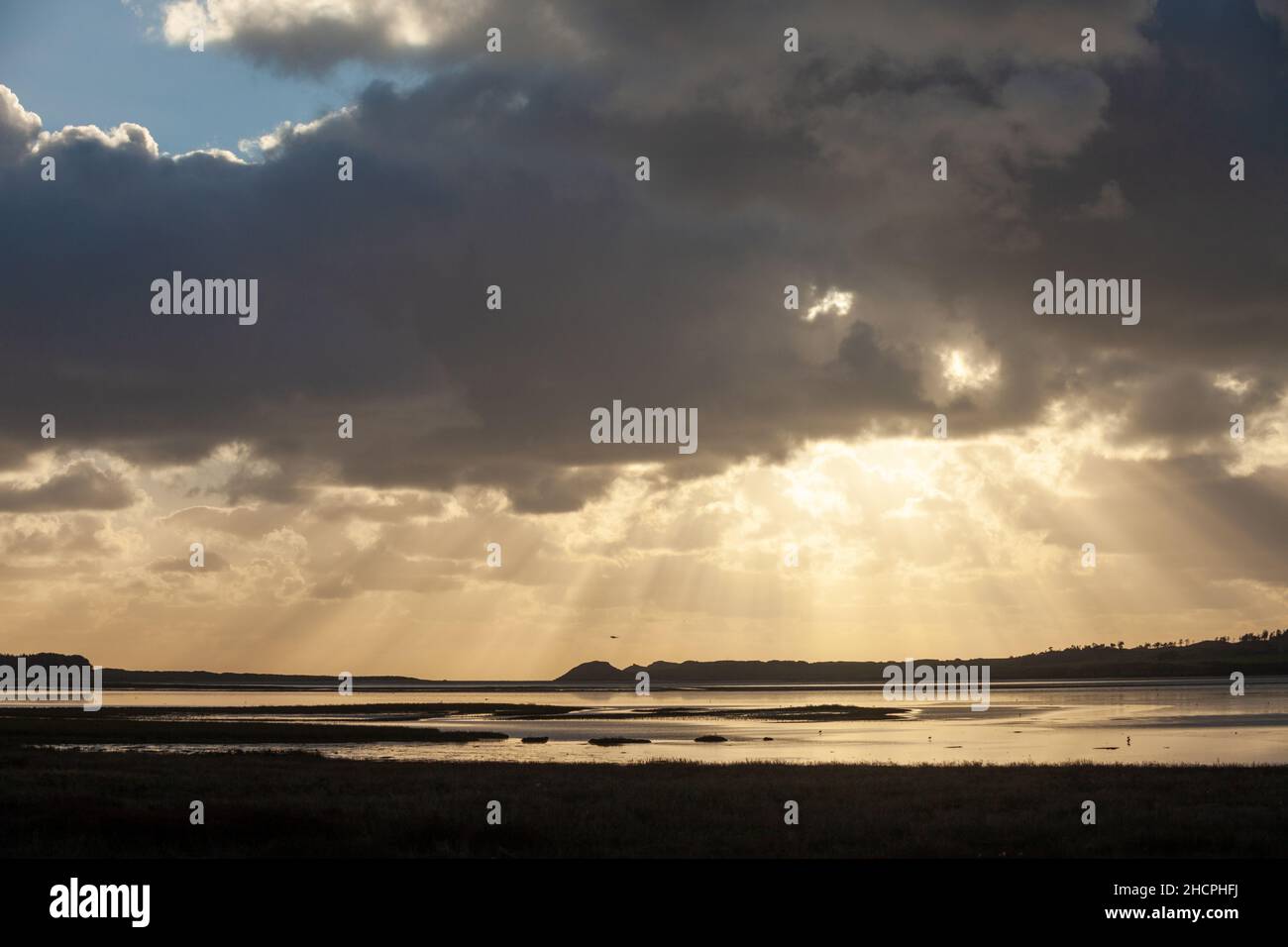 Shafts of sun ray light breaking through clouds at Malltraeth Anglesey ...