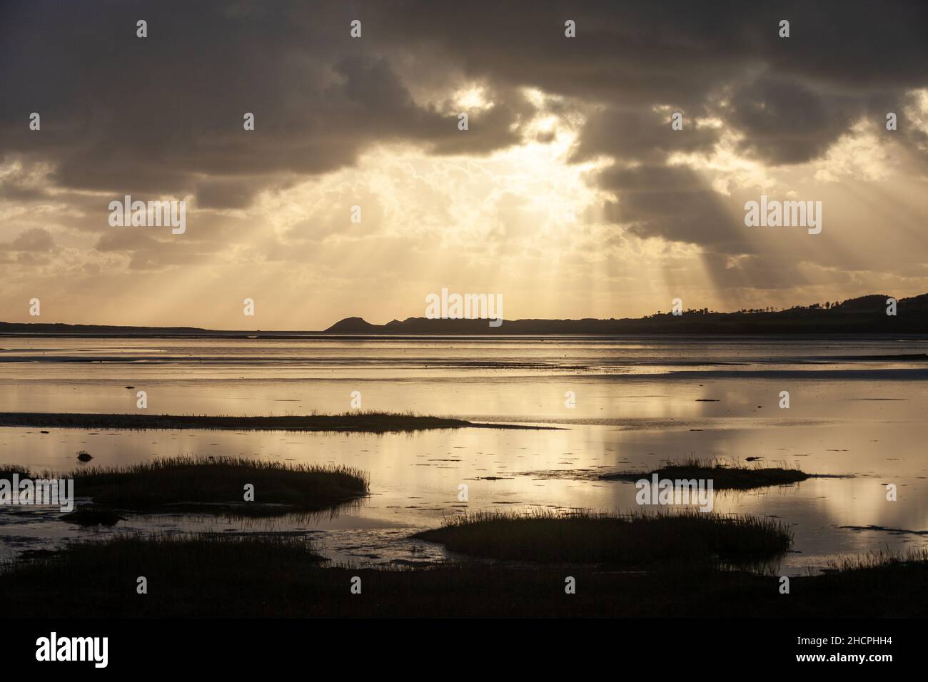 Shafts of sun ray light breaking through clouds at Malltraeth Anglesey ...