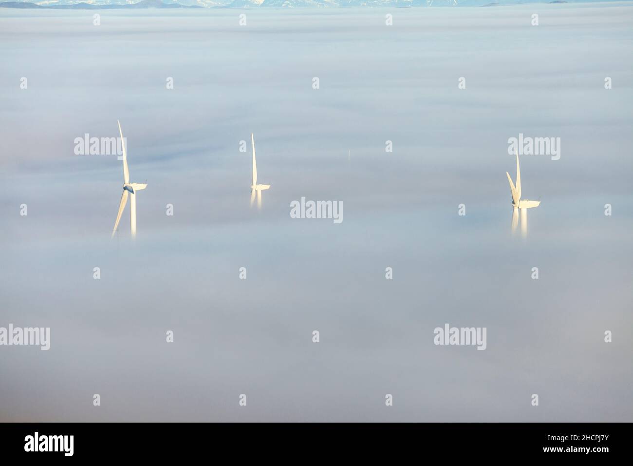 Wind turbines sticking out of clouds caused by a temperature inversion ...