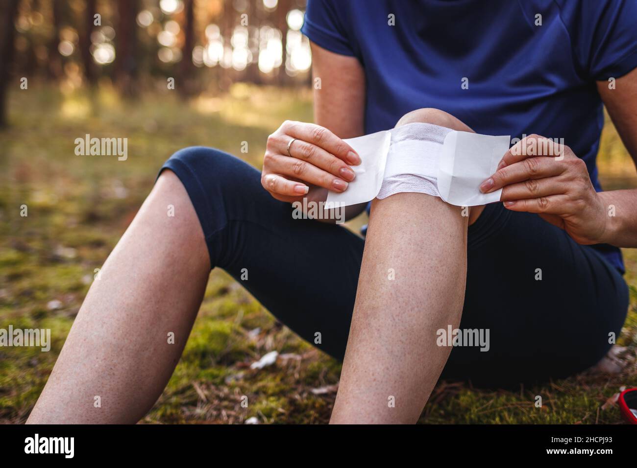 Injured woman sticking plaster or adhesive bandage at her knee. Health ...