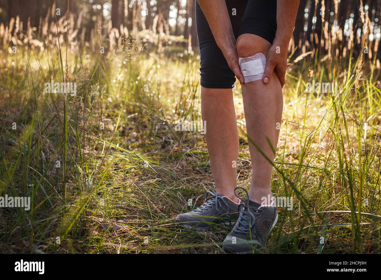Injured woman sticking plaster or adhesive bandage at her knee. Health ...